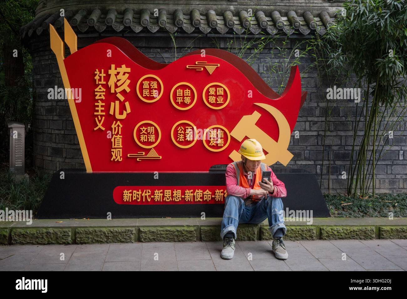 Worker sitting in front of a panel with the communist party symbol ...
