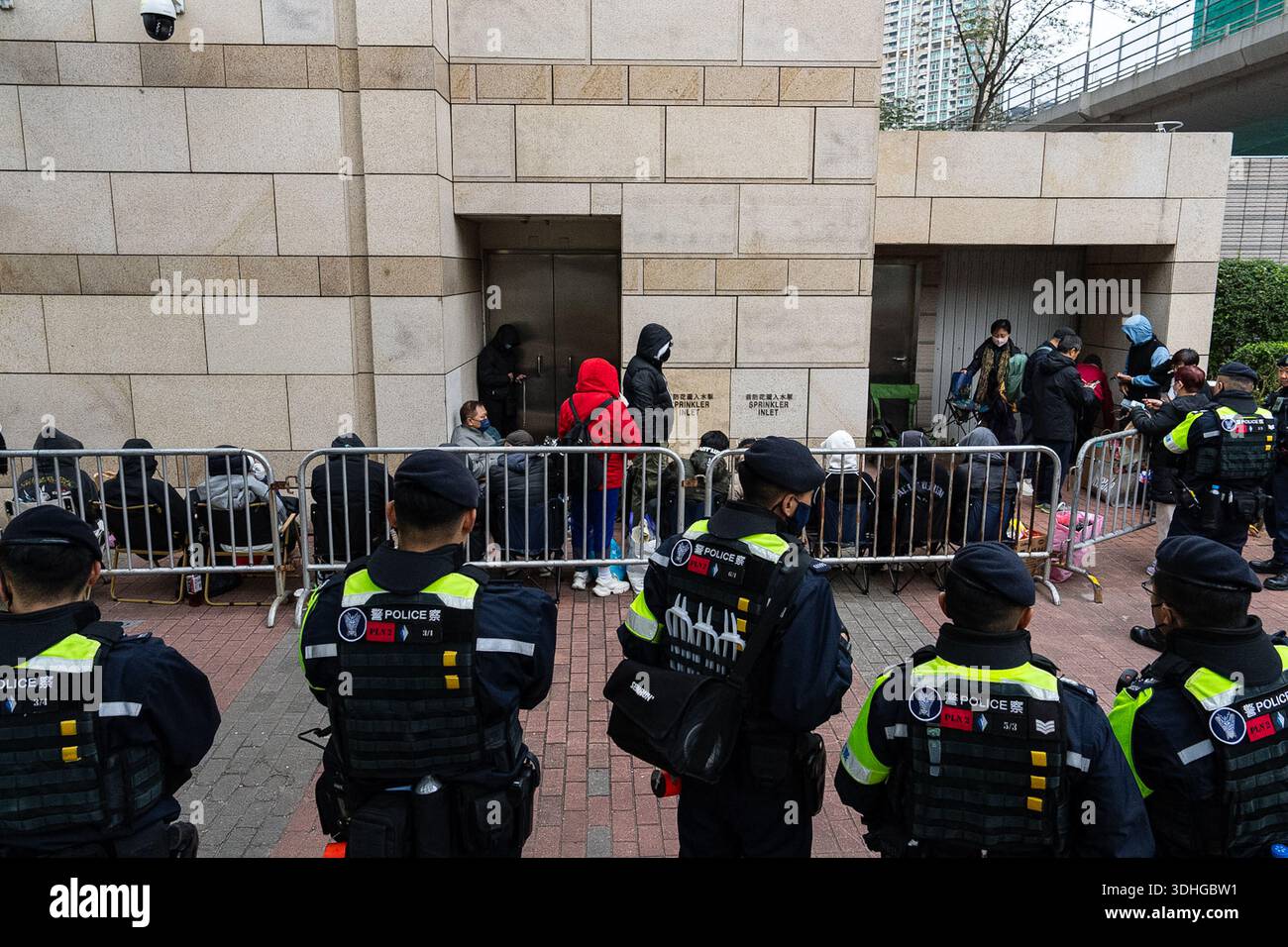 Police officers stand guard as people wait outside the West Kowloon ...