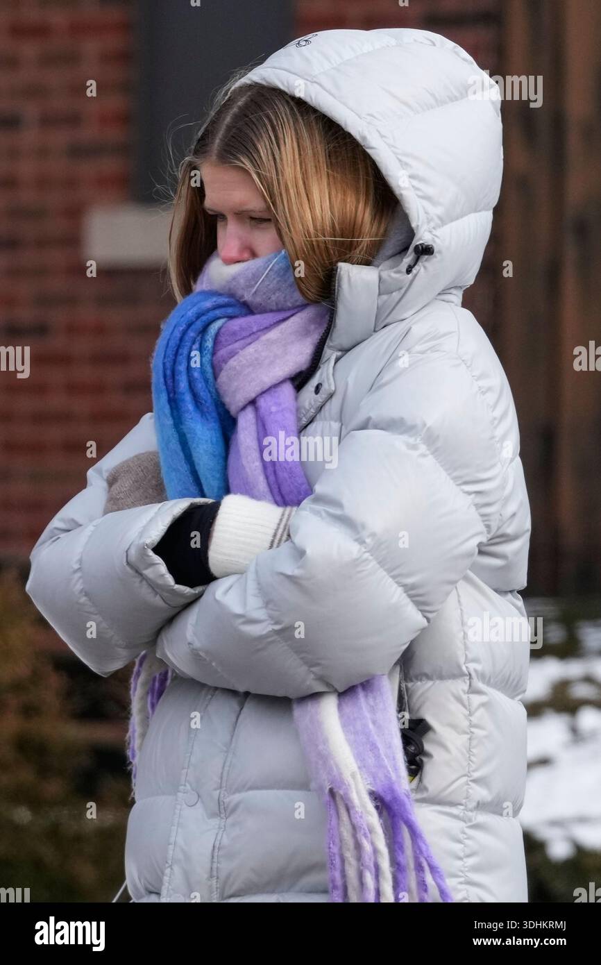 A pedestrian bundles up as they walk on a sidewalk during a cold ...