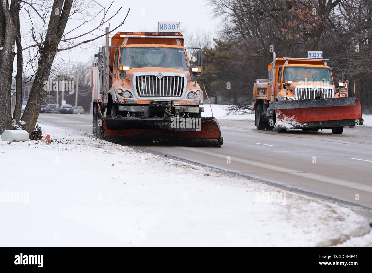 Snow plows drive through a street during cold weather in Northbrook ...