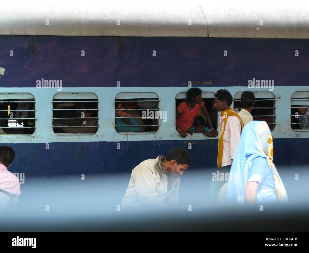 Passengers lean from windows of a crowded train at a railway station in ...