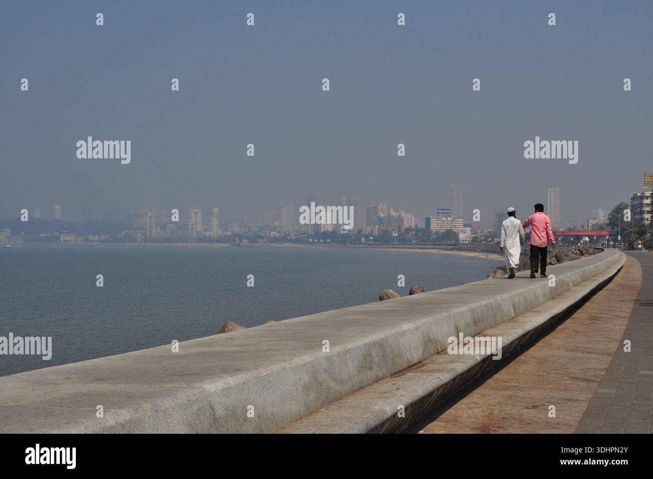 People walk along the Marine Drive promenade with the Mumbai skyline in ...