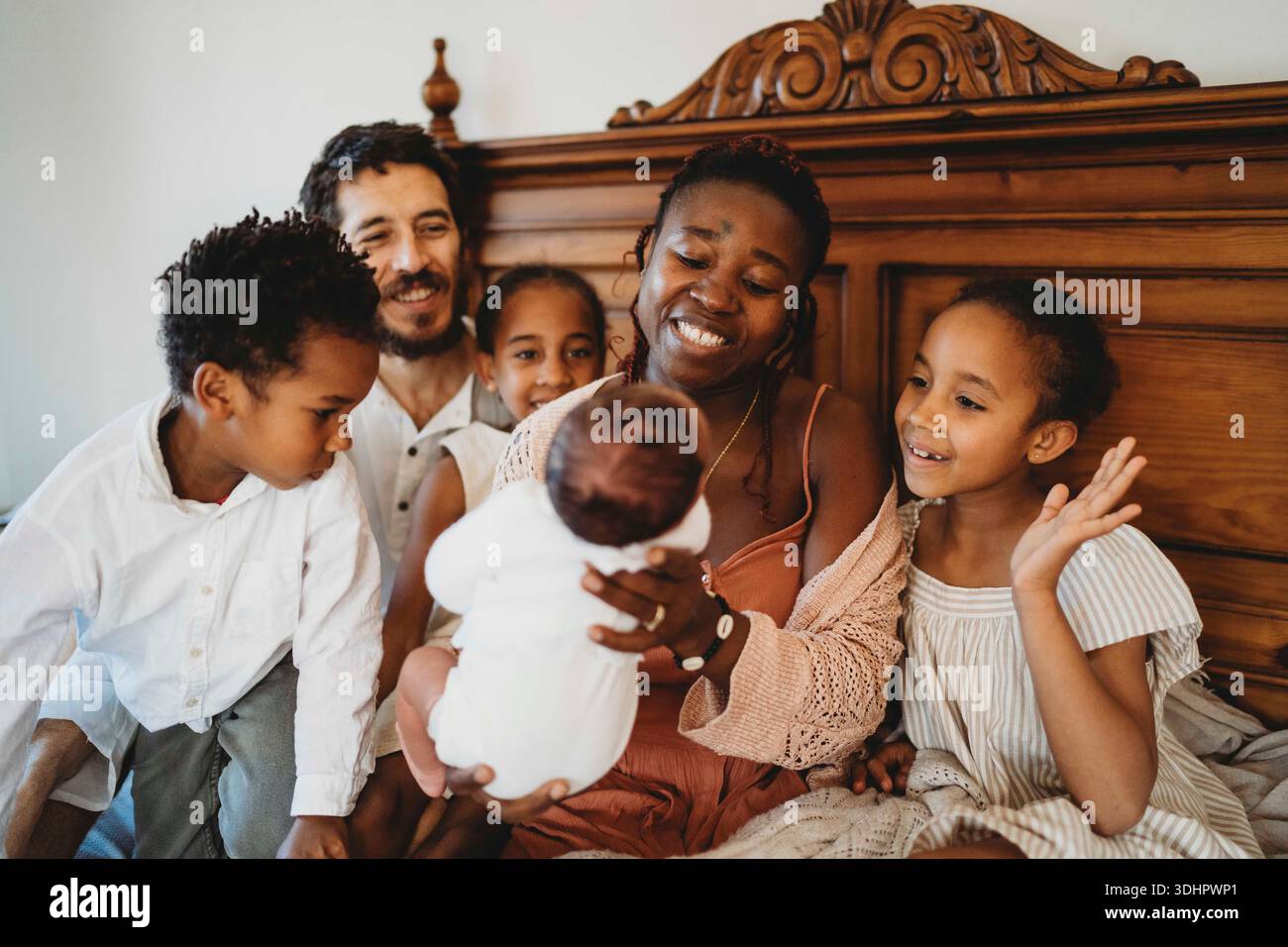 Large Multiracial family in bed black mom white dad smiling newborn ...