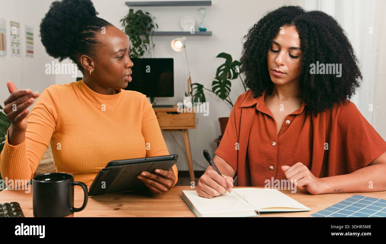 Collaborative Team Meeting Between Two Women At Desk With Notebook And ...
