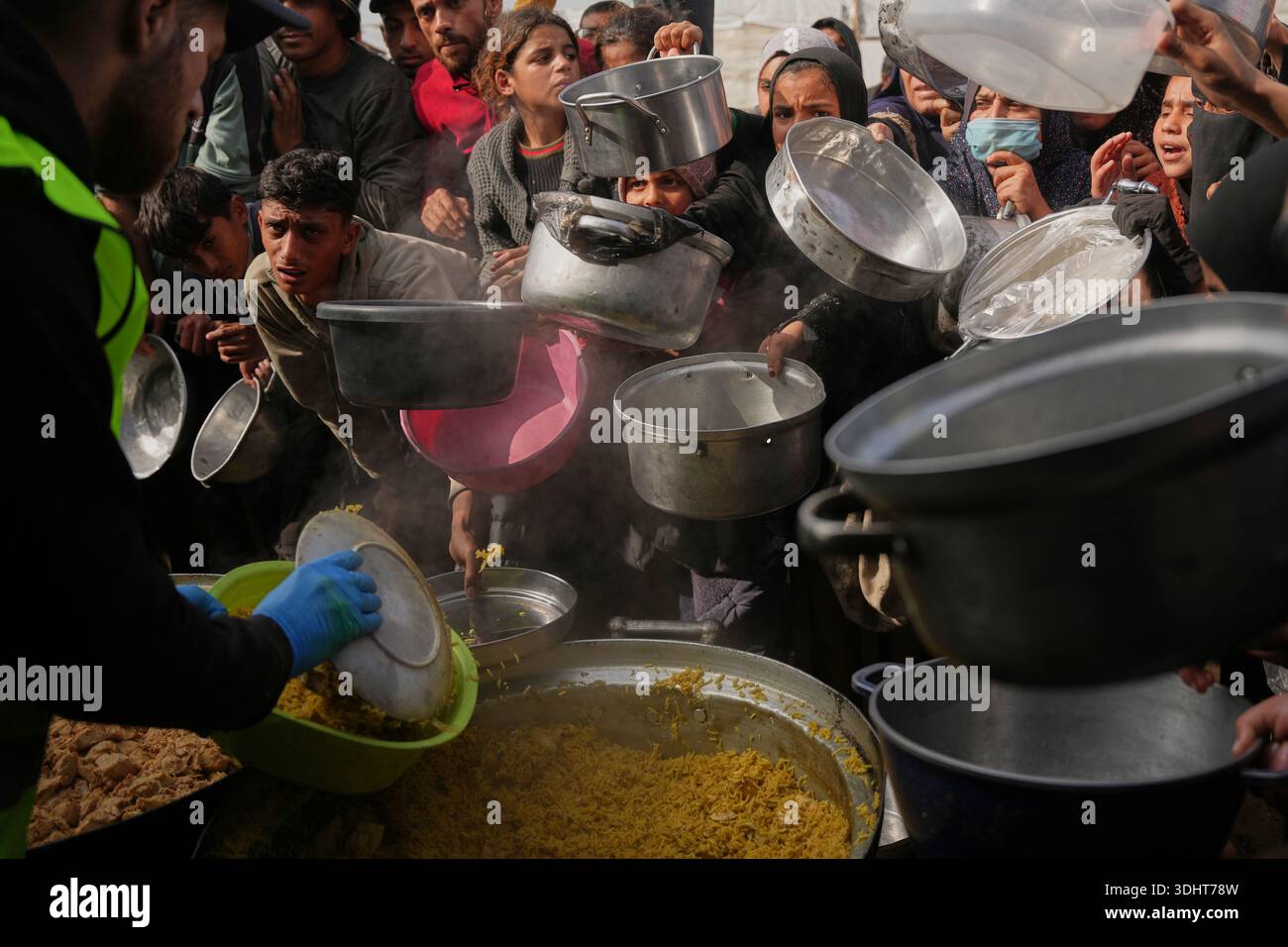 Palestinians wait to receive donated food at a distribution center in ...