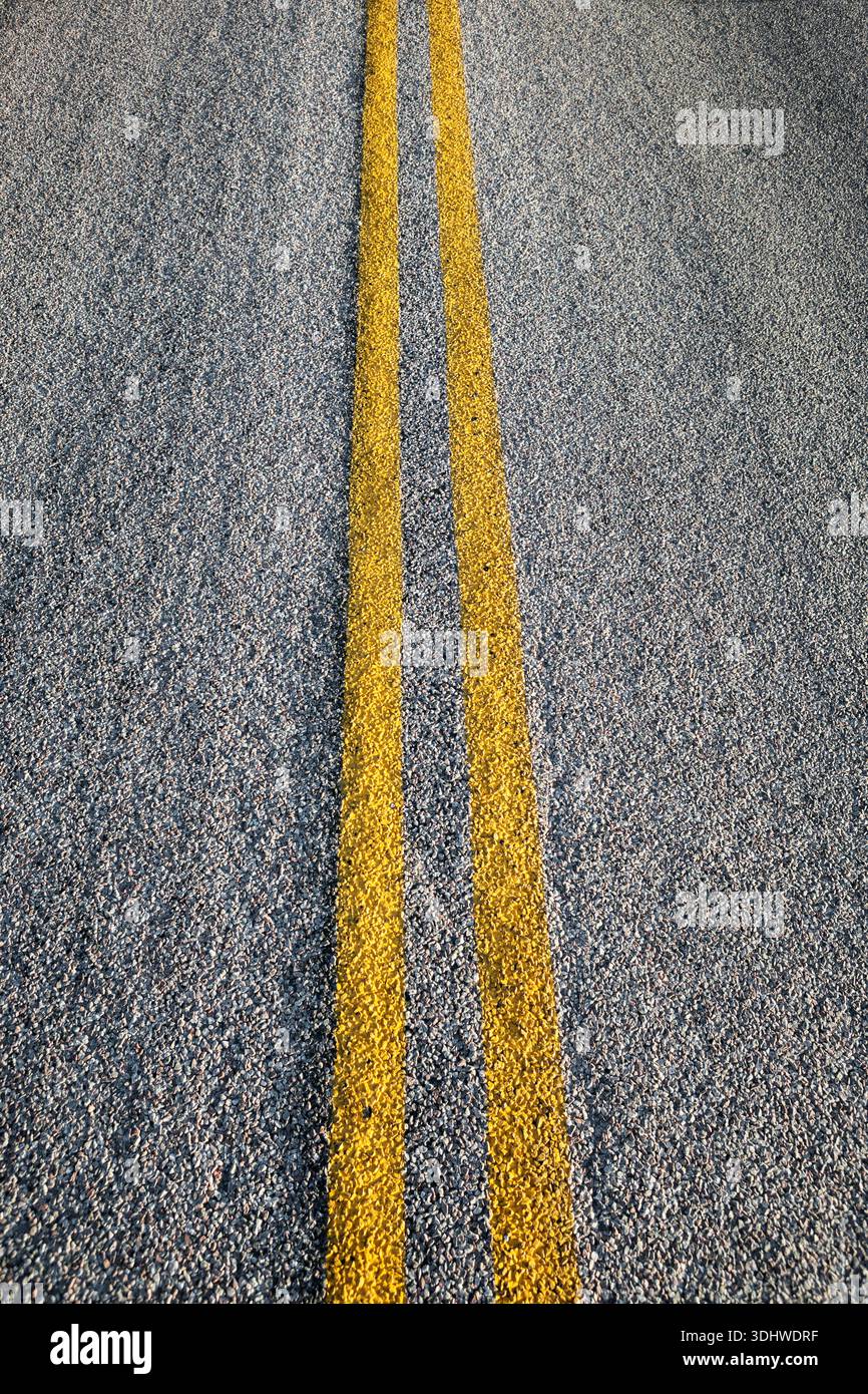 Double yellow lines painted on an asphalt road, symbolizing travel ...