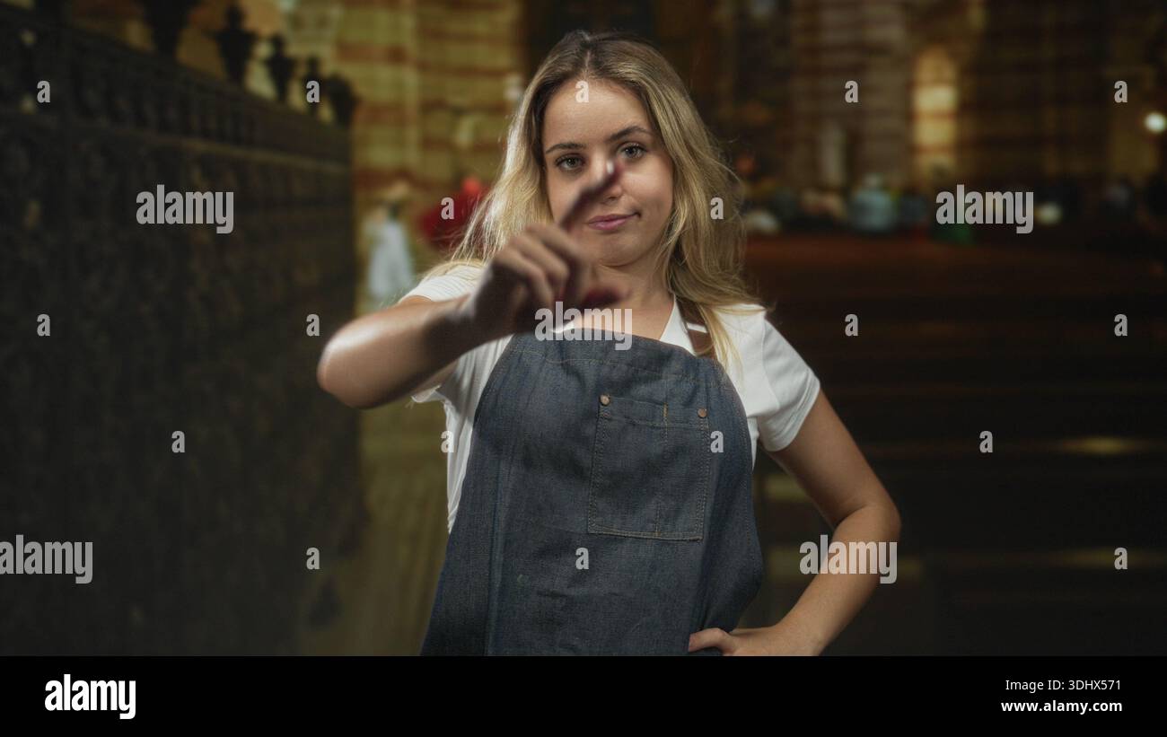 Woman in denim apron with hands on hips inside a church building ...
