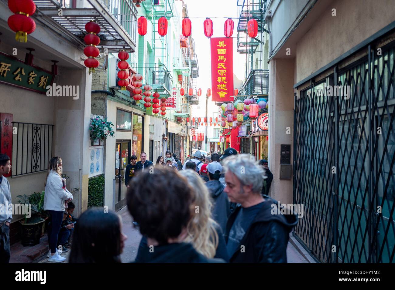 Crowded pedestrian alley with red lanterns and storefronts in Chinatown ...