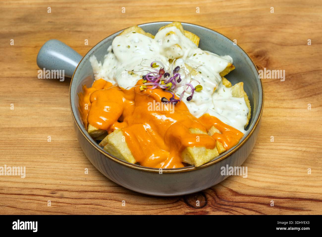 Patatas bravas served in a small cast-iron casserole dish, still ...
