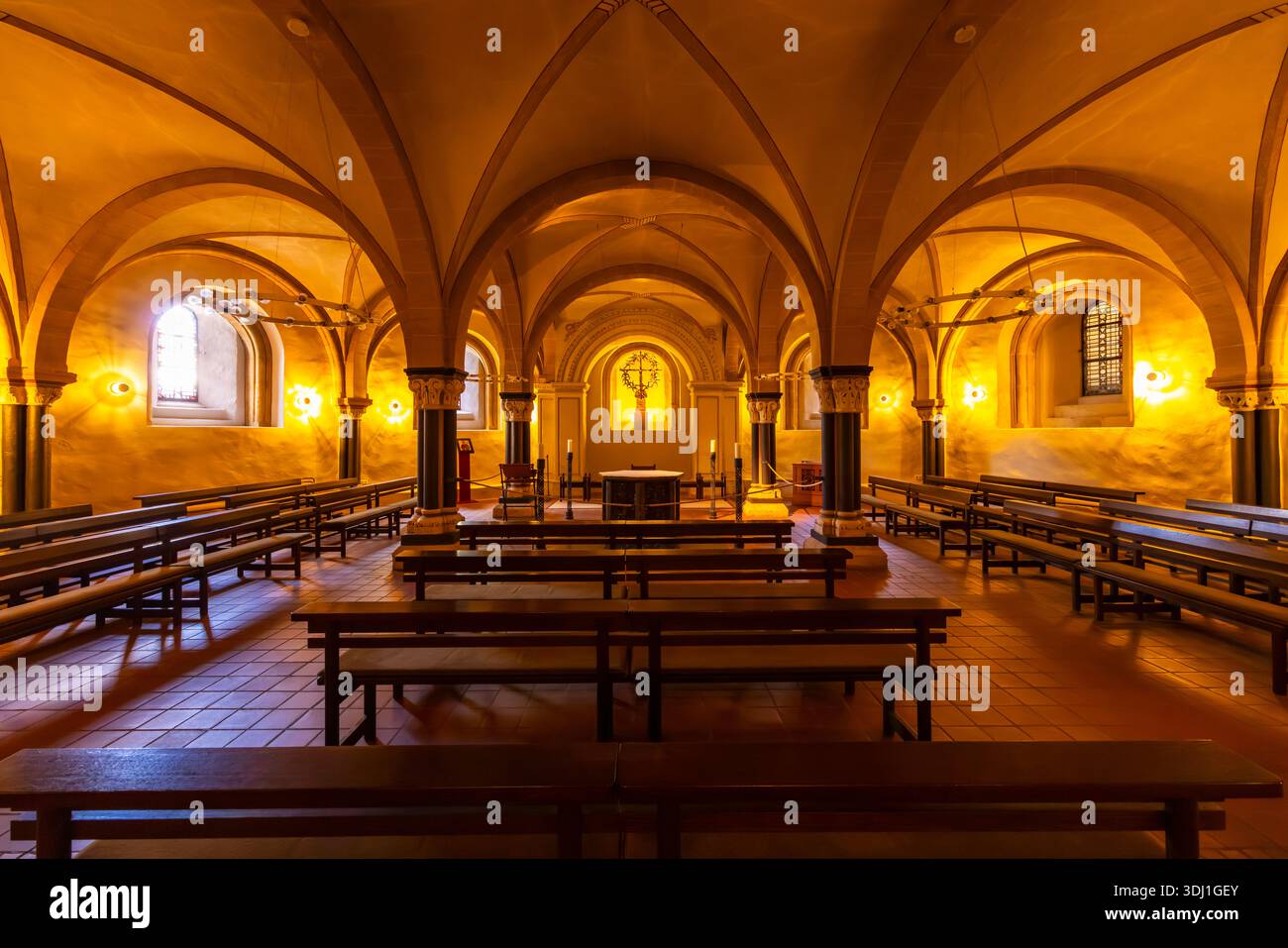 Crypt interior featuring vaulted arches, rows of benches, and an altar ...