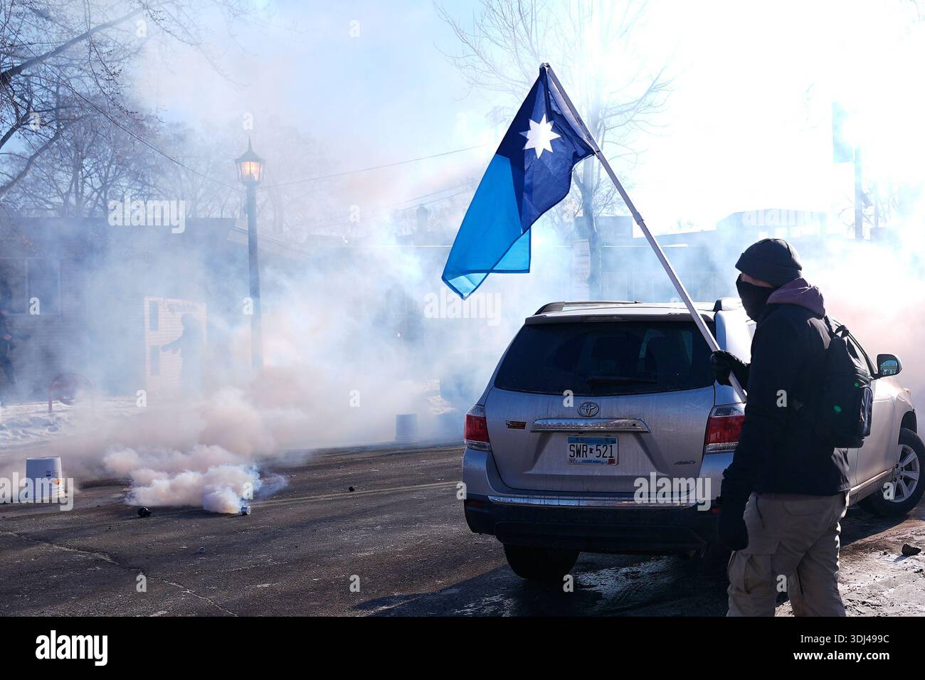 A person holds a Minnesota state flag as Federal immigration officers ...