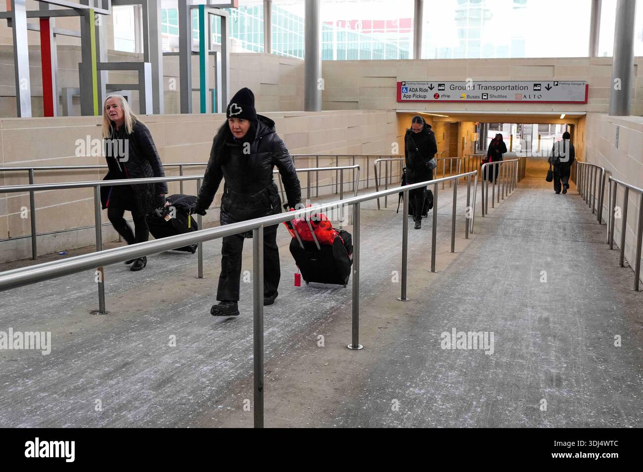 Travelers walk up a salt-covered sidewalk that lead into the main ...