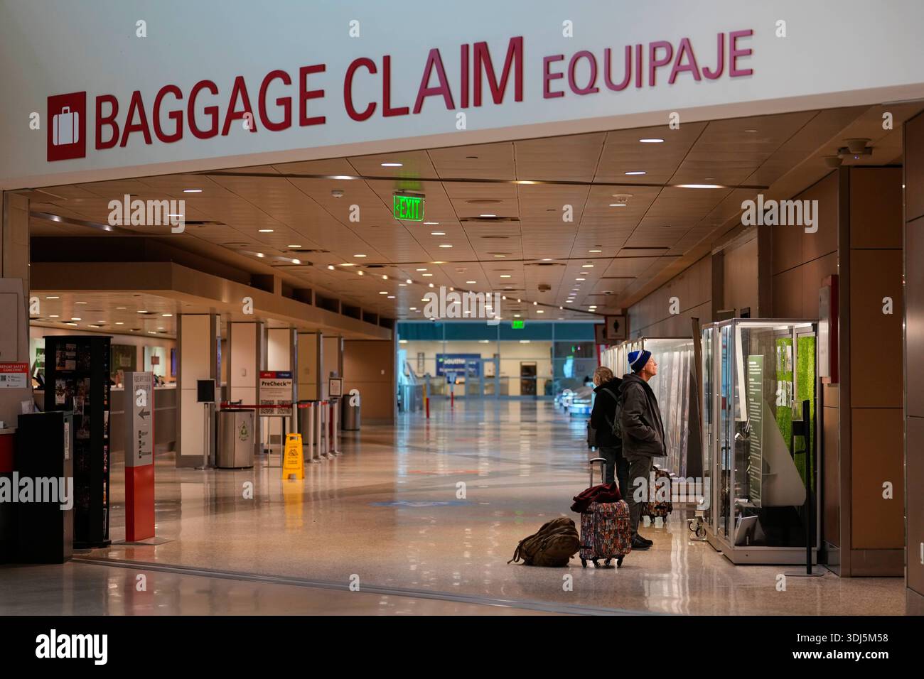 A pair a travelers look at an exhibit near baggage claim where ...