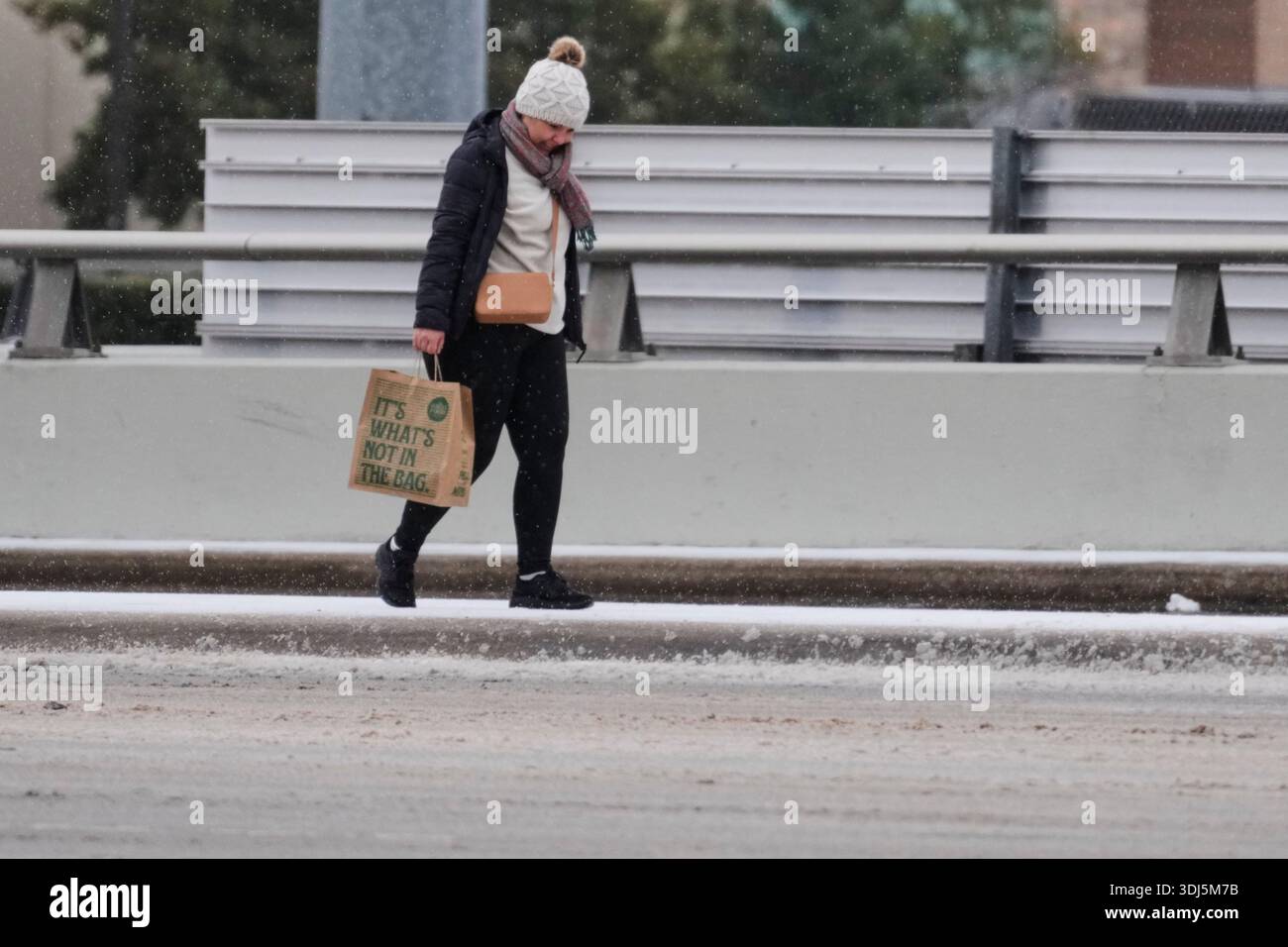 A person walks on an icy sidewalk over the Dallas North tollway ...