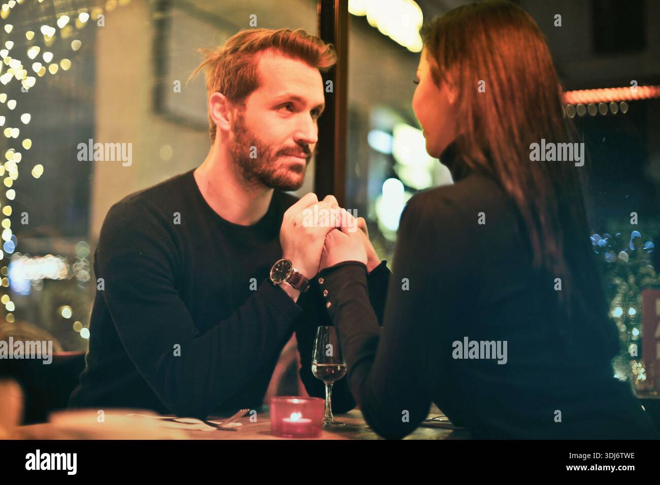 Couple holding hands across a table during a romantic dinner date with ...