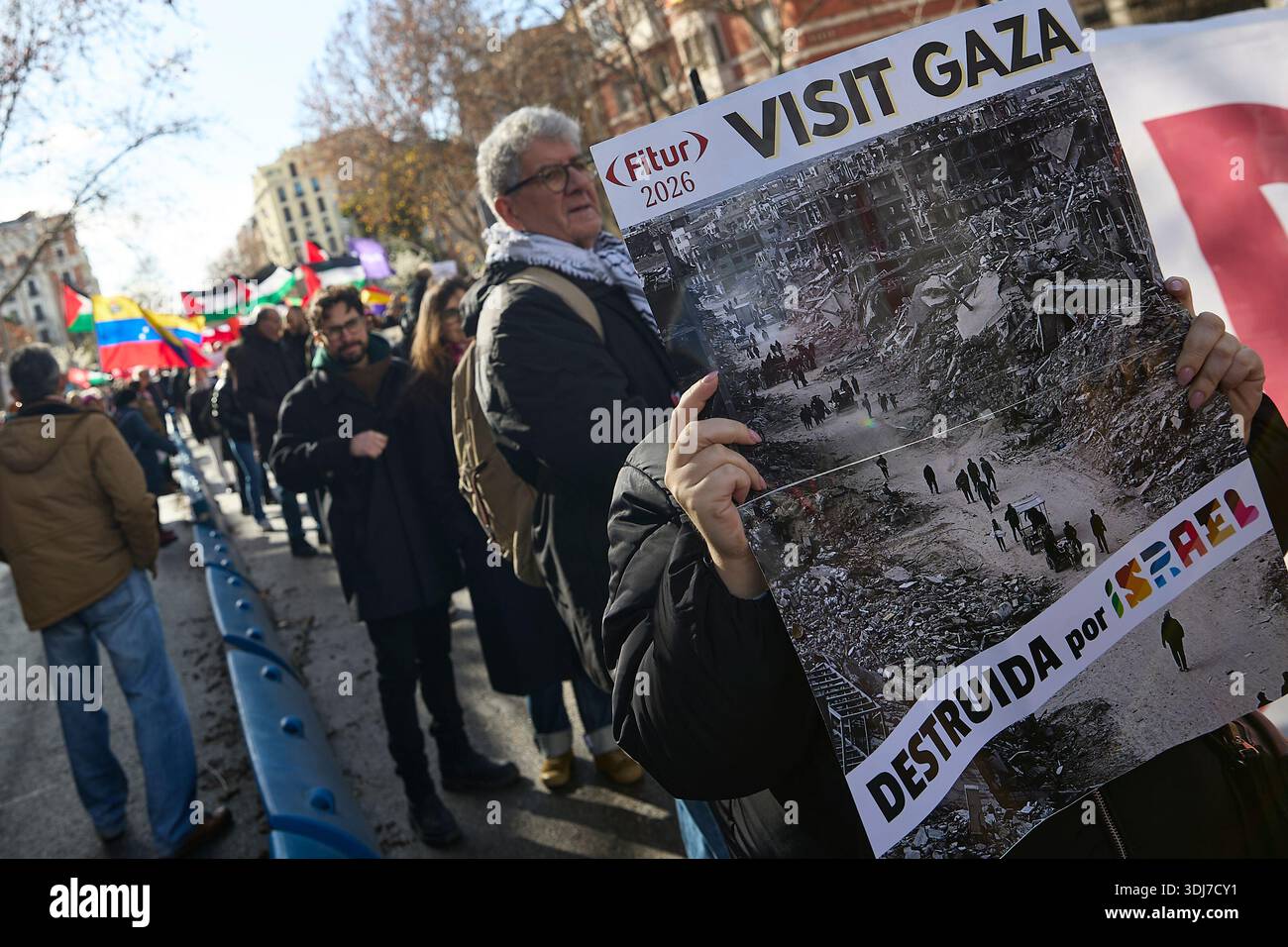 Demonstrator carries banner with slogan 'Fitur 2026. Visit Gaza ...