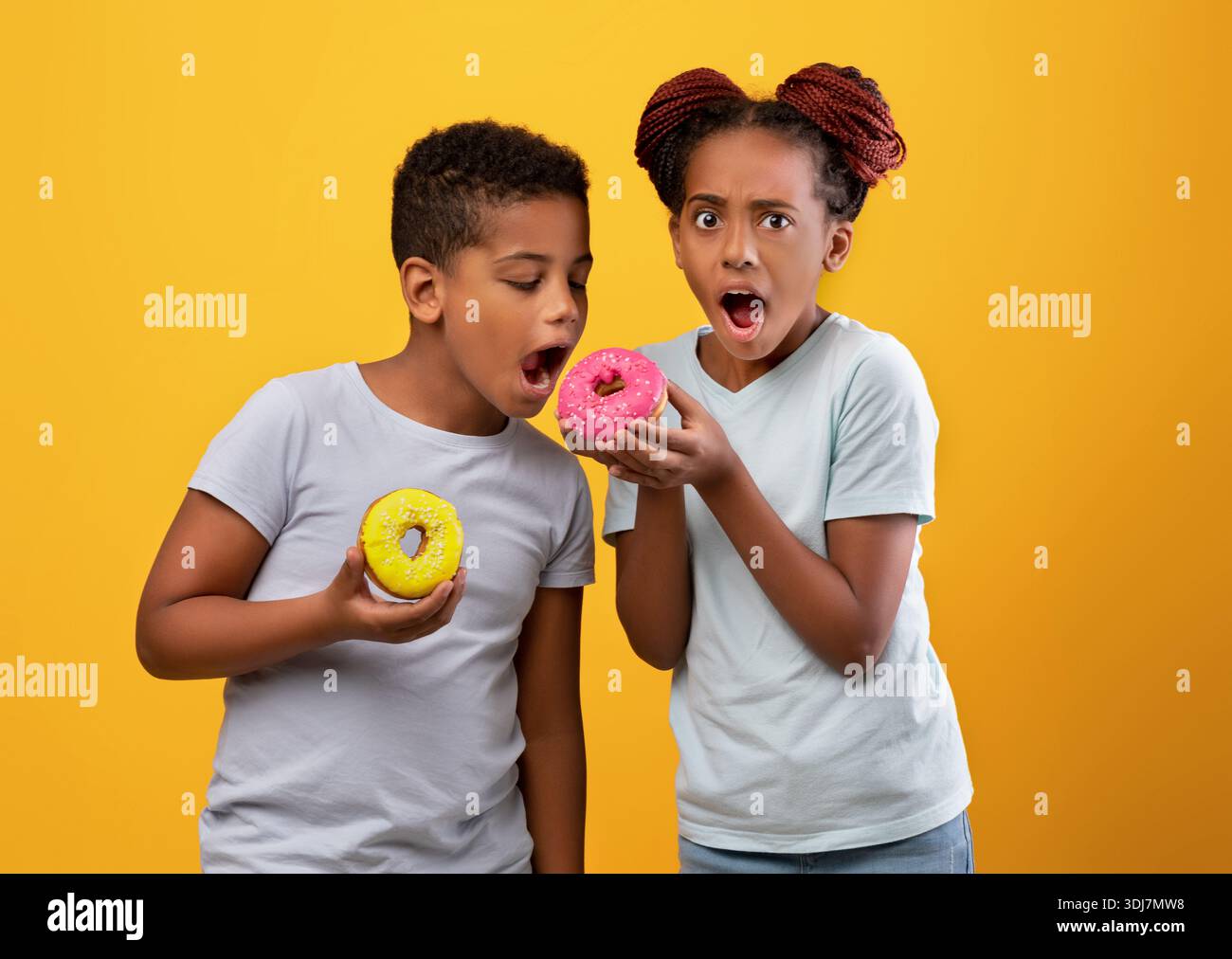 Sweet-tooth black guy biting his sisters donut Stock Photo - Alamy