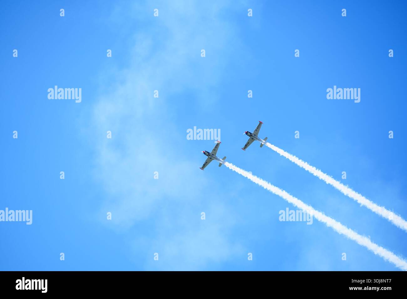 Two stunt planes perform an aerial maneuver, leaving dramatic smoke ...