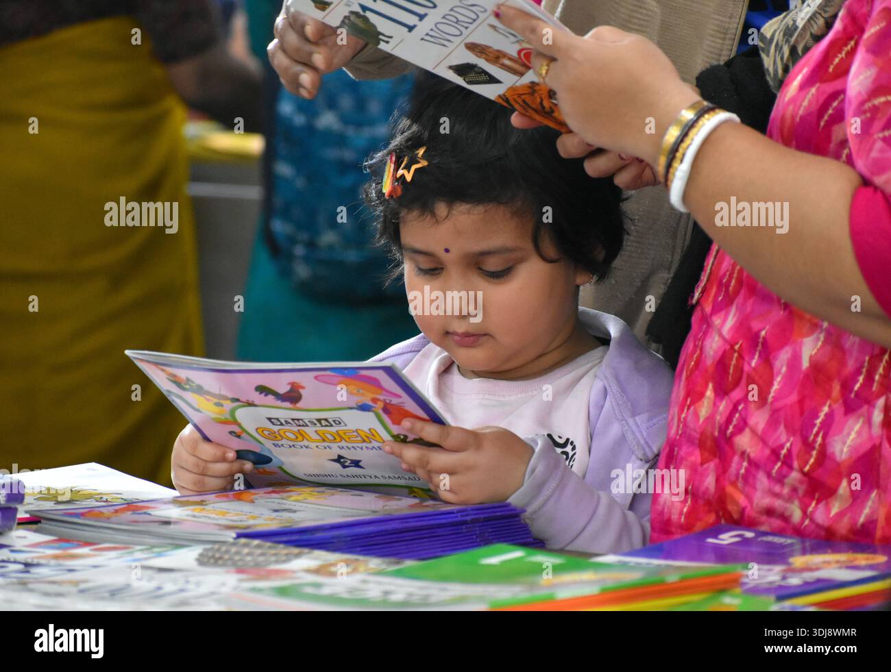 A little girl reads a storybook in a book stall at the International ...