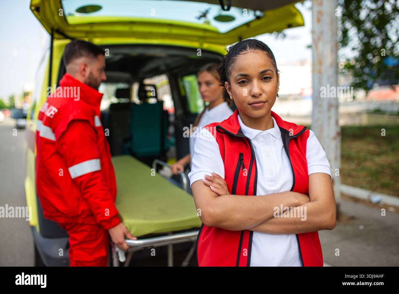 Young female african american paramedic standing rear of the ambulance ...
