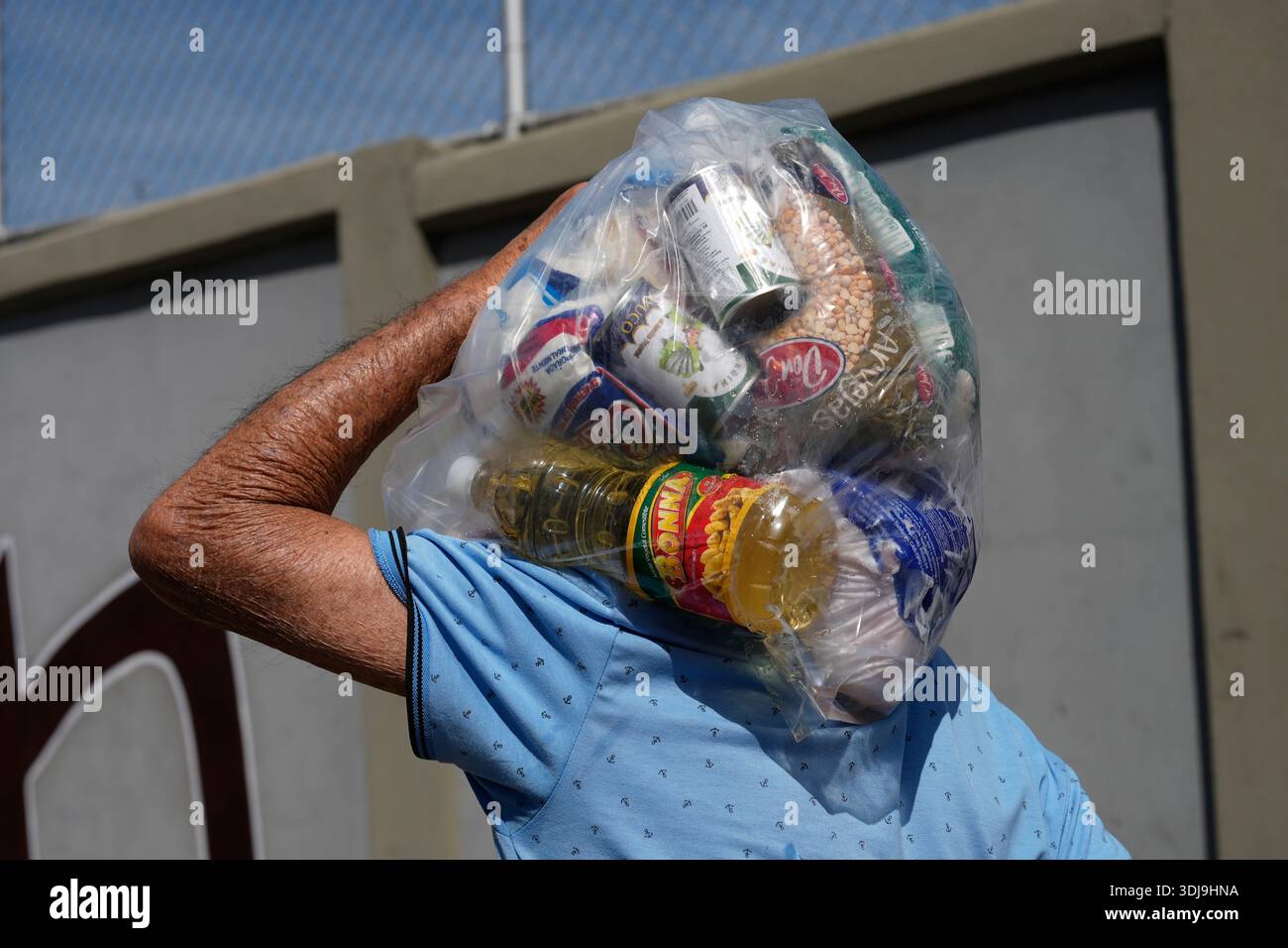 A shopper carries a bag of food at a government-subsidized market in ...