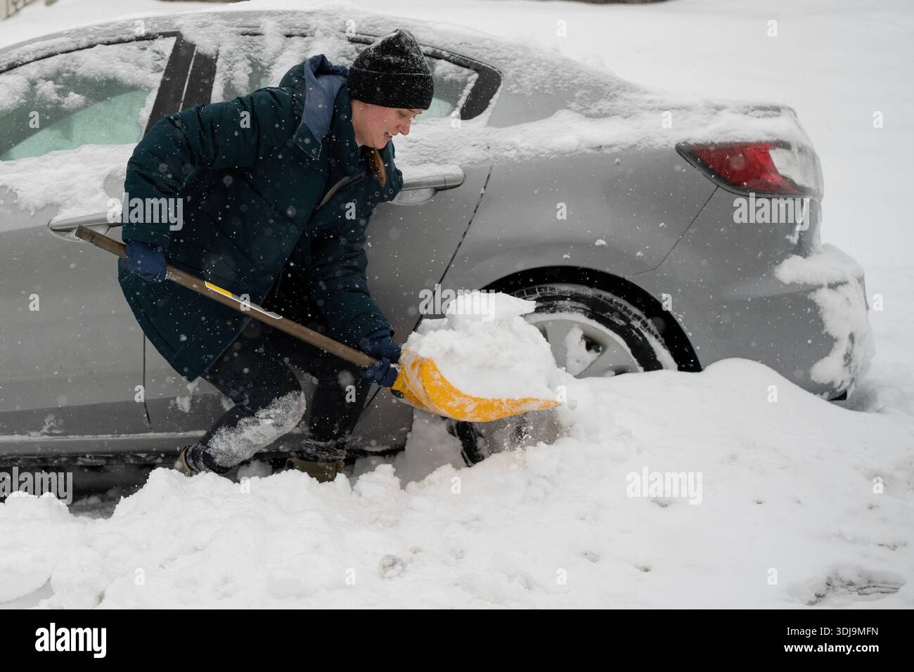 Anna Knappenberger digs snow from around her car during a winter storm ...