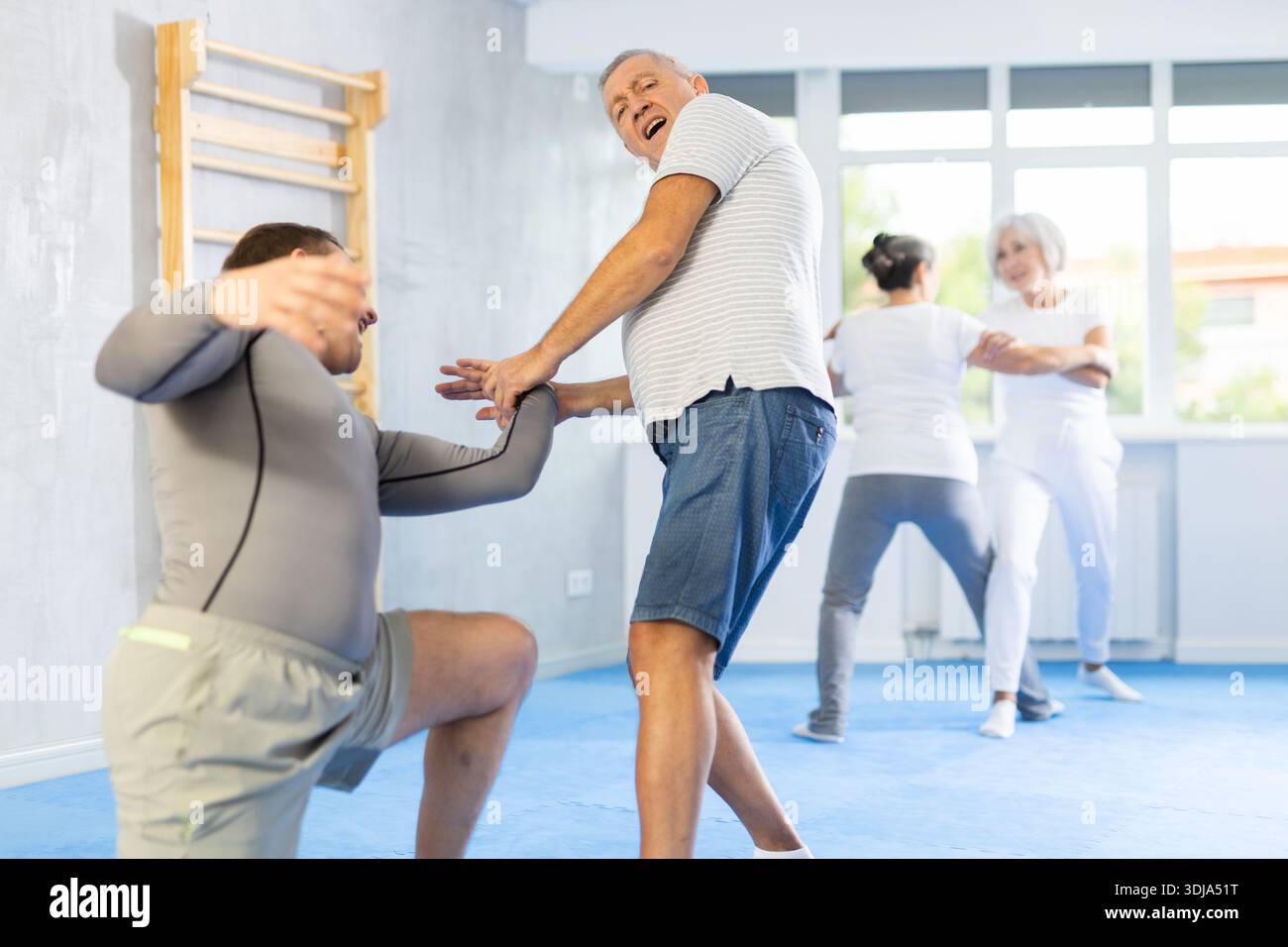 Old man twisting her opponent's arm during self-defense classes Stock ...