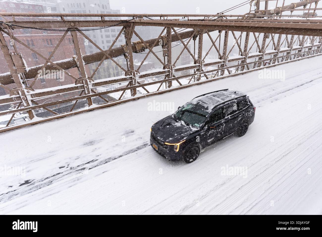 Lonely car driven on snow covered Brooklyn Bridge roadway during Sunday ...