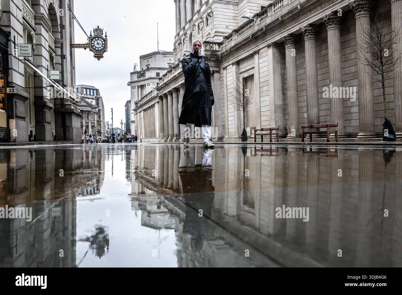 A man walks in his rain jacket in central London in front of the Bank ...
