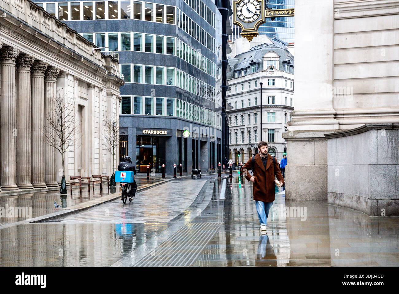 A man walks on a rainy day in central London in front of the Bank of ...