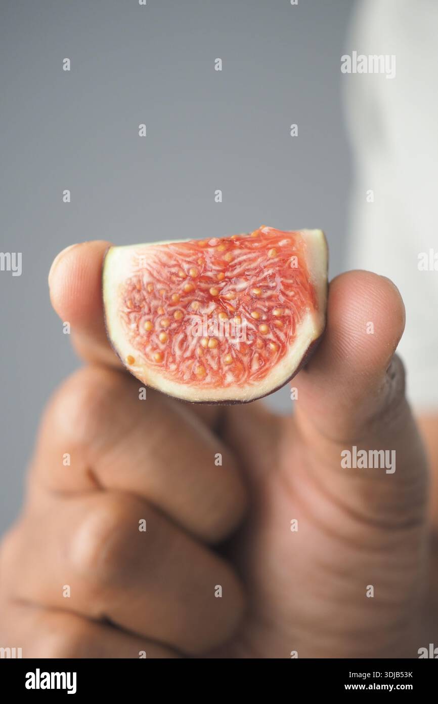 Hand holds a cut fig with inside showing details Stock Photo - Alamy