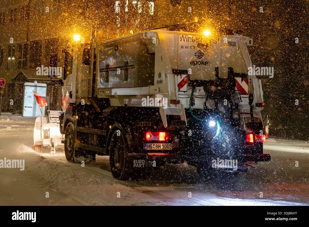Rear view of municipal snowplow truck spreading grit while clearing ...