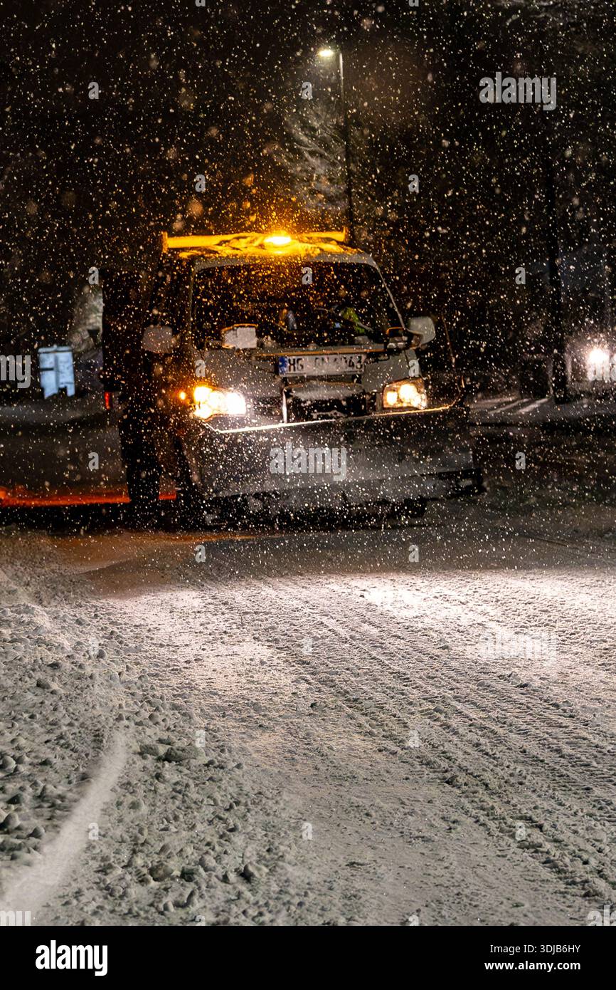 Snow-covered road illuminated by streetlights during intense nighttime ...