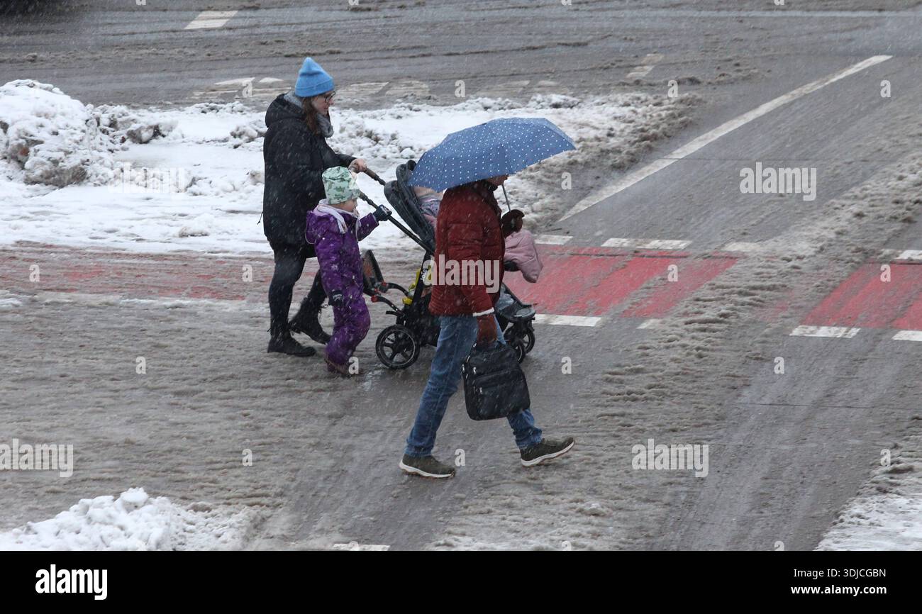 Passanten gehen am Montagmorgen im Schneetreiben über eine Ampel ...