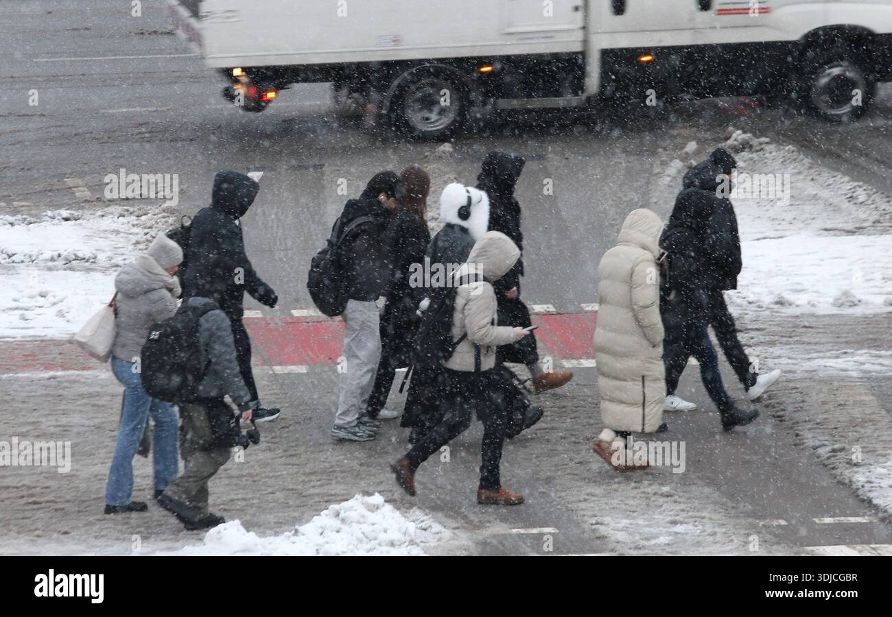 Passanten gehen am Montagmorgen im Schneetreiben über eine Ampel ...