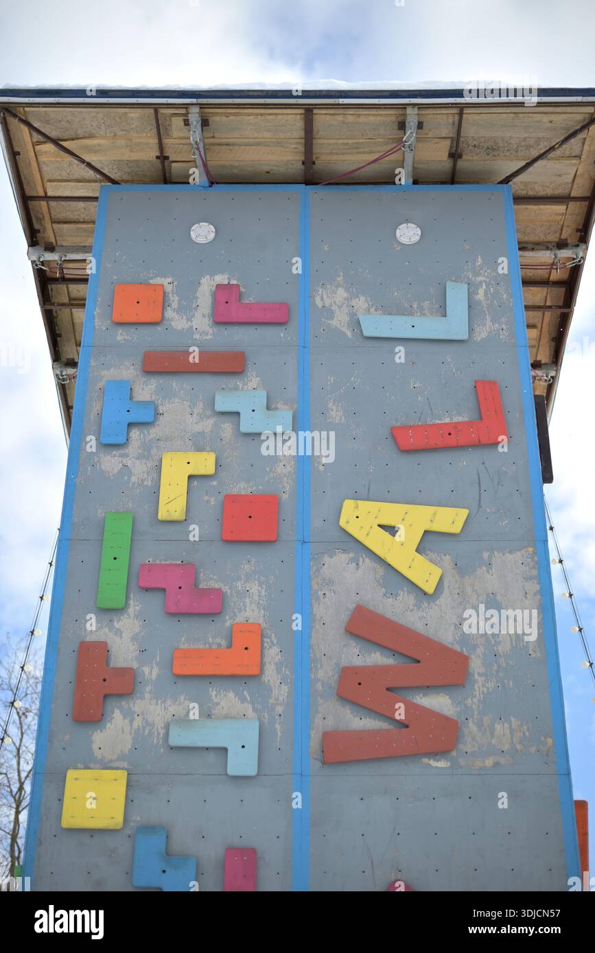 A colorful climbing wall with various shapes and letters, set against a ...