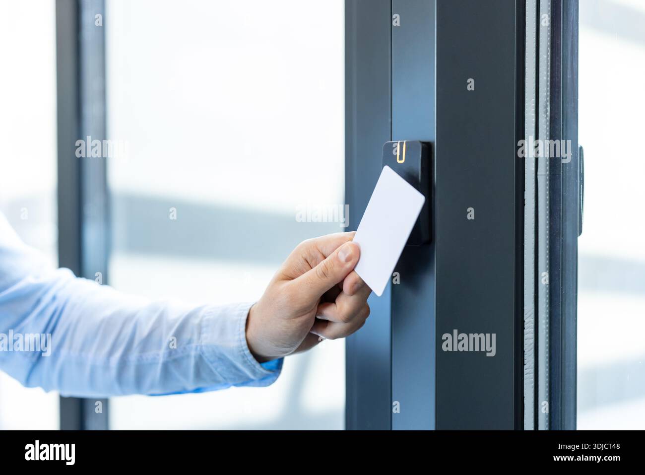 Hand holding white access card to an rfid reader, unlocking an ...