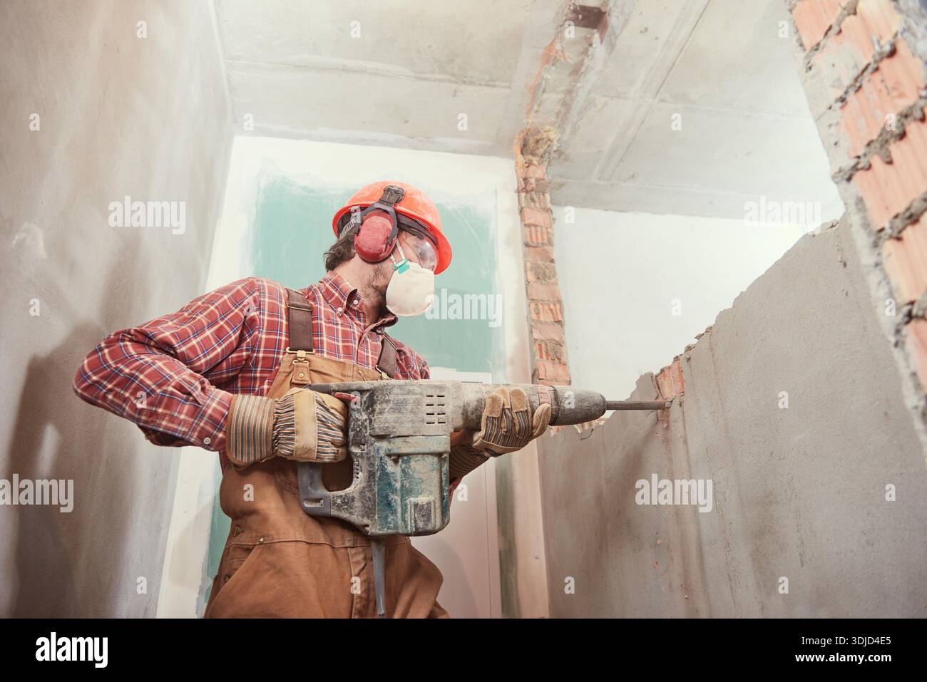 Worker with personal protection equipment and demolition hammer at ...