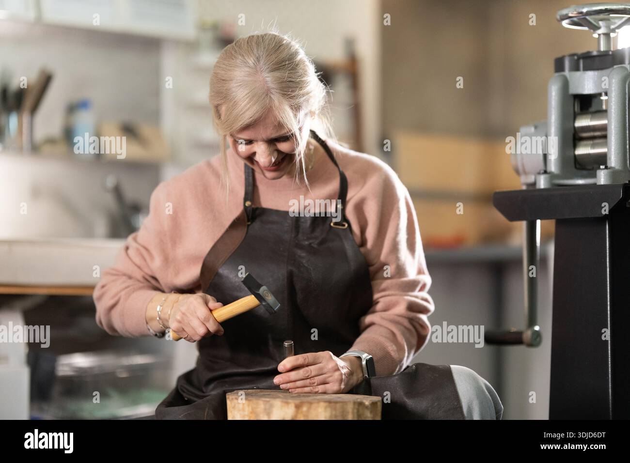 Woman smithing metal using hammer and punch tool Stock Photo - Alamy