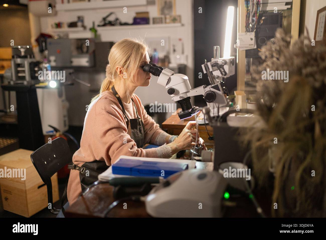 Craftswoman examining details using a microscope in workshop Stock ...
