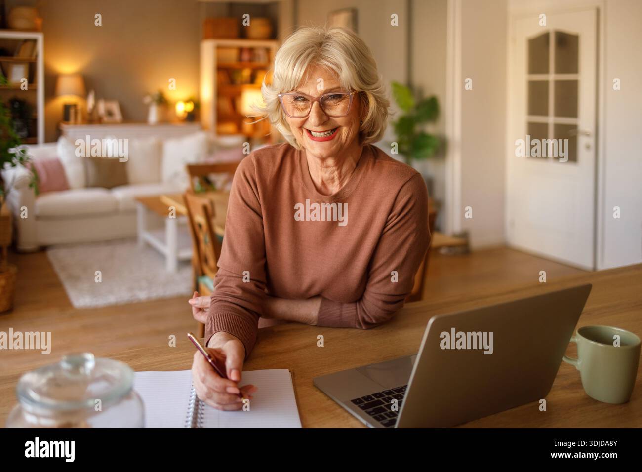 Portrait of happy senior woman making utility bill payments on laptop ...