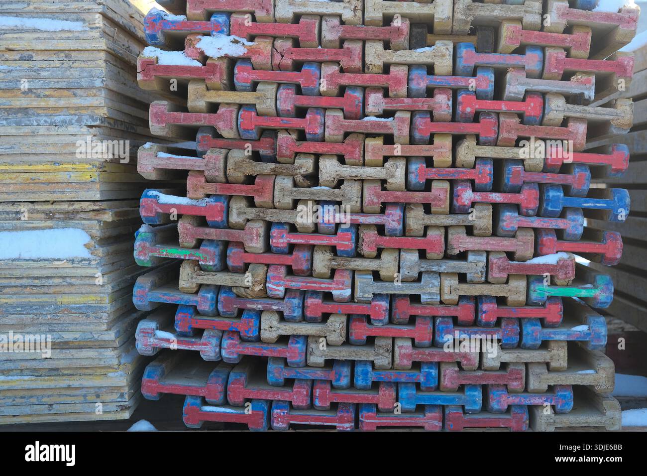 Tight front view of stacked wood formwork with chipped red and blue ...