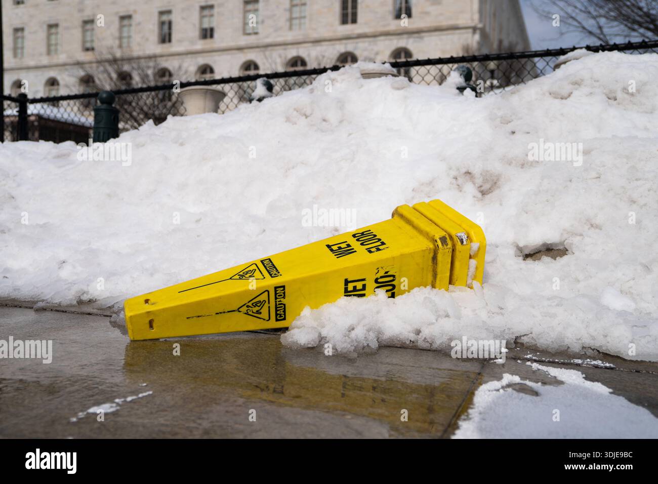 A wet floor sign sits in a pile of snow off of the Capitol South metro ...