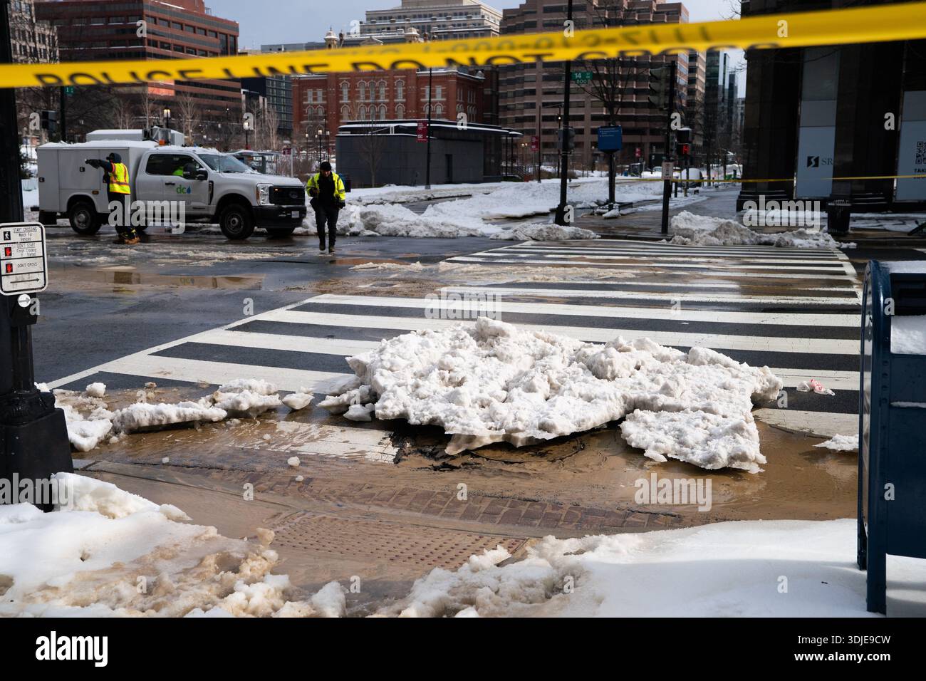 DC Water crews work around snow piles to repair a water main break ...