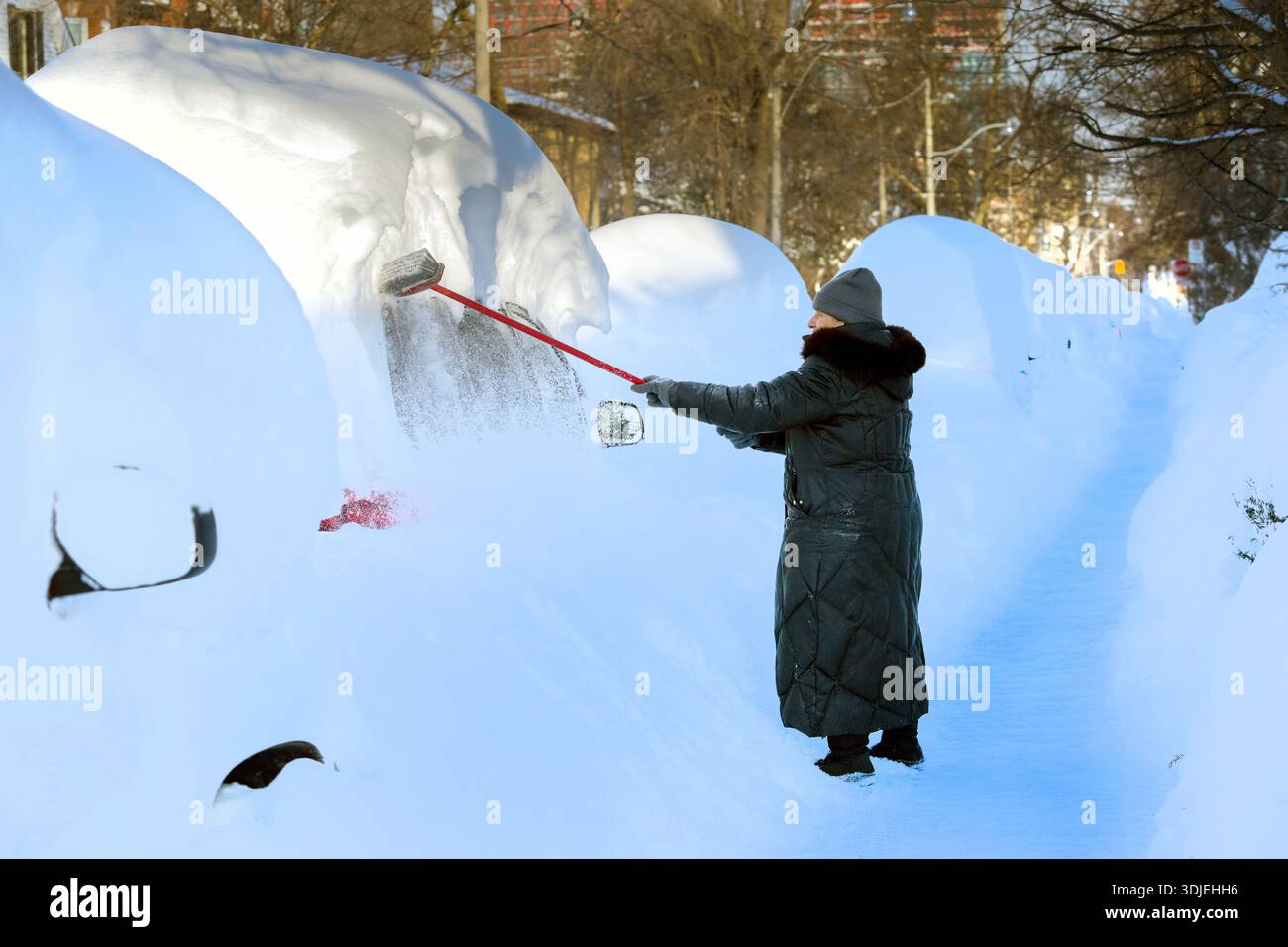 A woman tries to sweep snow off her van after a massive snowstorm hit ...