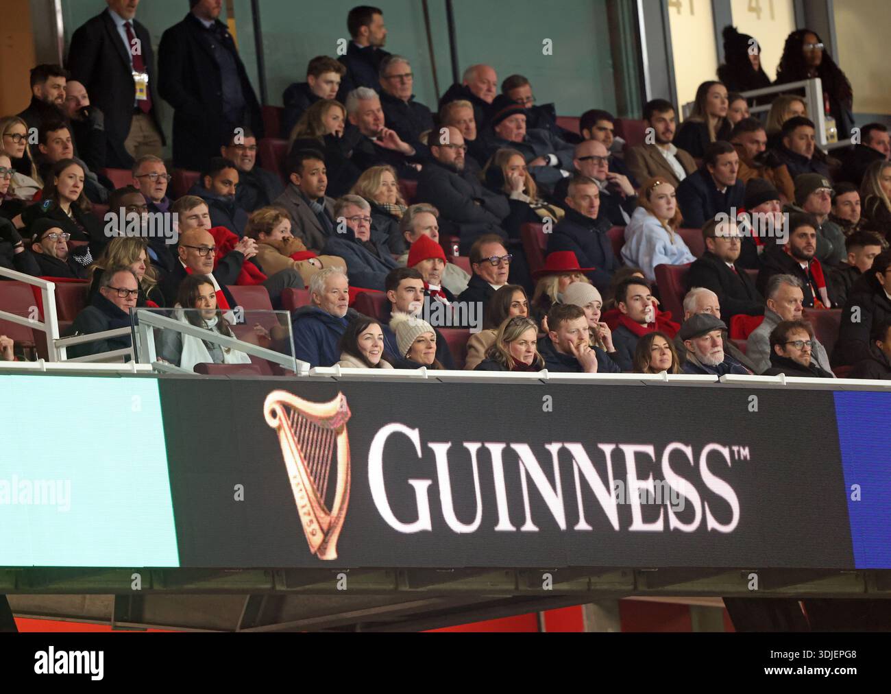 Fans watching the game, behind a Guinness advertisement at the Arsenal ...