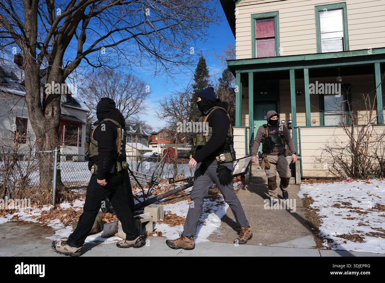 Federal immigration officers walk away after knocking on a door Monday ...