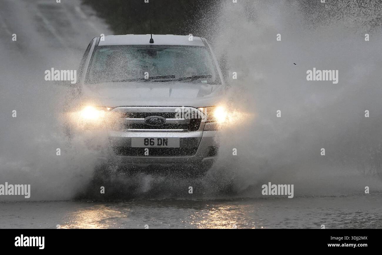 A car passes through a flooded area of the A20 near Ashford in Kent ...