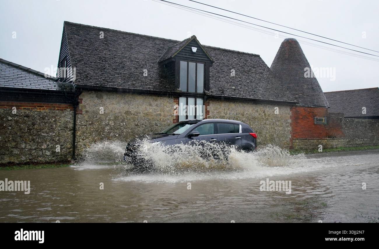 A car passes through a flooded road in Ashford, Kent. Storm Chandra ...