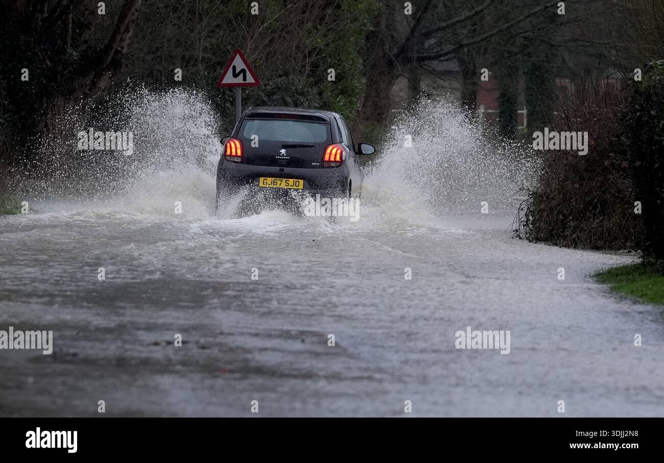 A car passes through a flooded road in Ashford, Kent. Storm Chandra ...